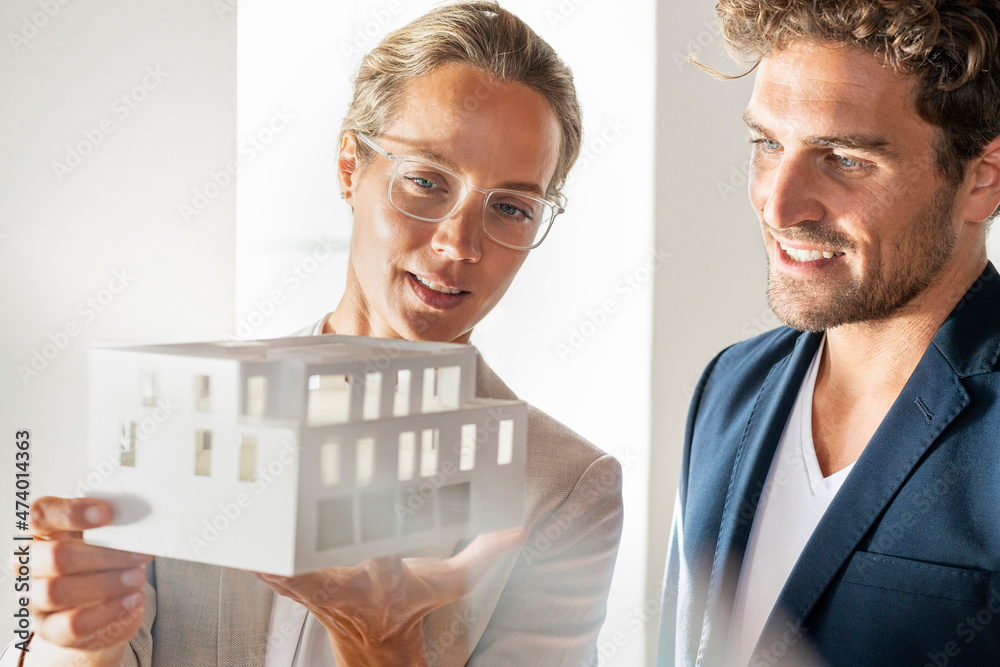 Male and female professional with architectural model working together ...