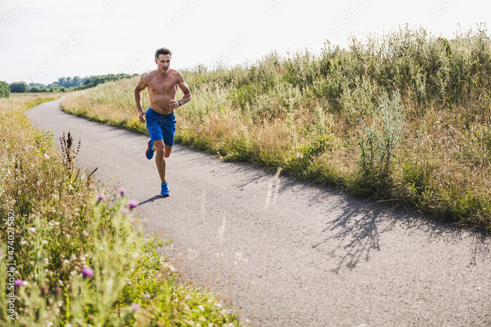 Shirtless male athlete running on road Stock Photo | Adobe Stock