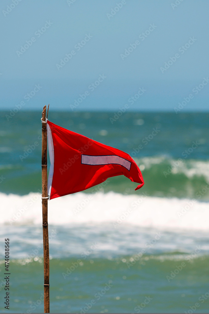 Red flag lifeguard danger warning sign on the beach. No swimming it's ...