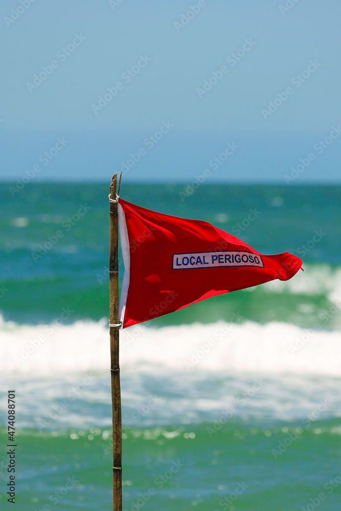 Red flag lifeguard danger warning sign on the beach. No swimming it's ...