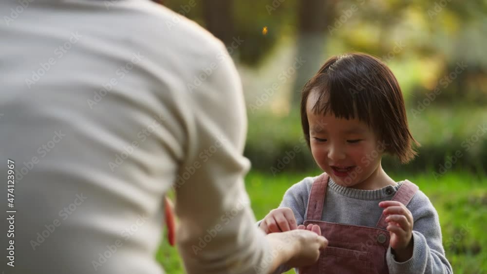 lovely asian baby girl grab snacks from mother's palm outdoor in the ...