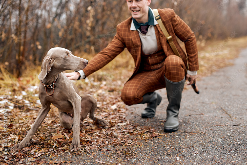caucasian nice Hunter man with gray hunting dog in forest. man sitting ...