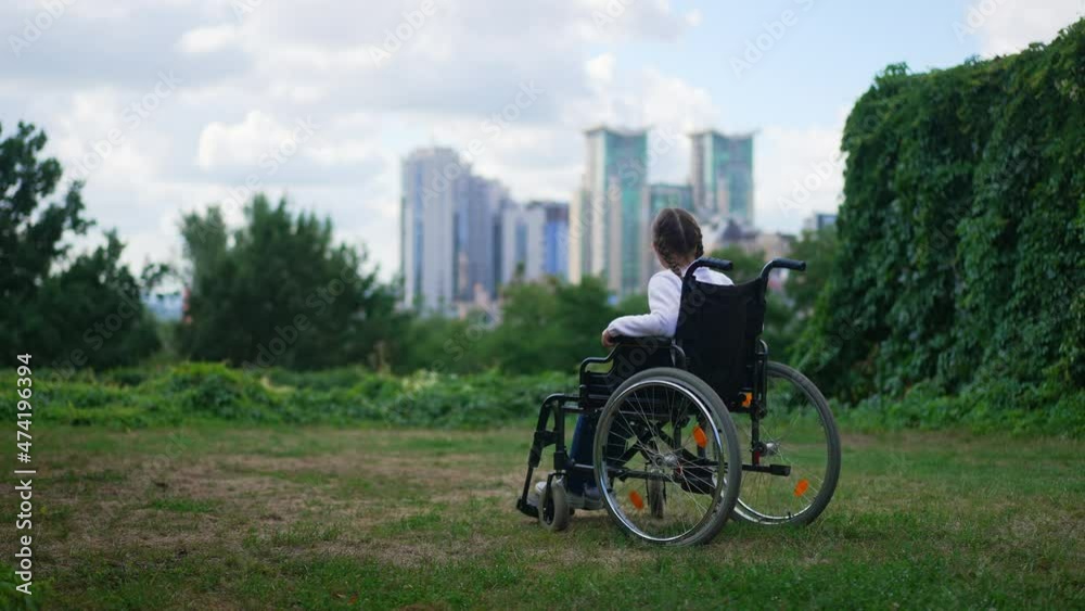 Wide shot summer park with disabled Caucasian girl in wheelchair ...