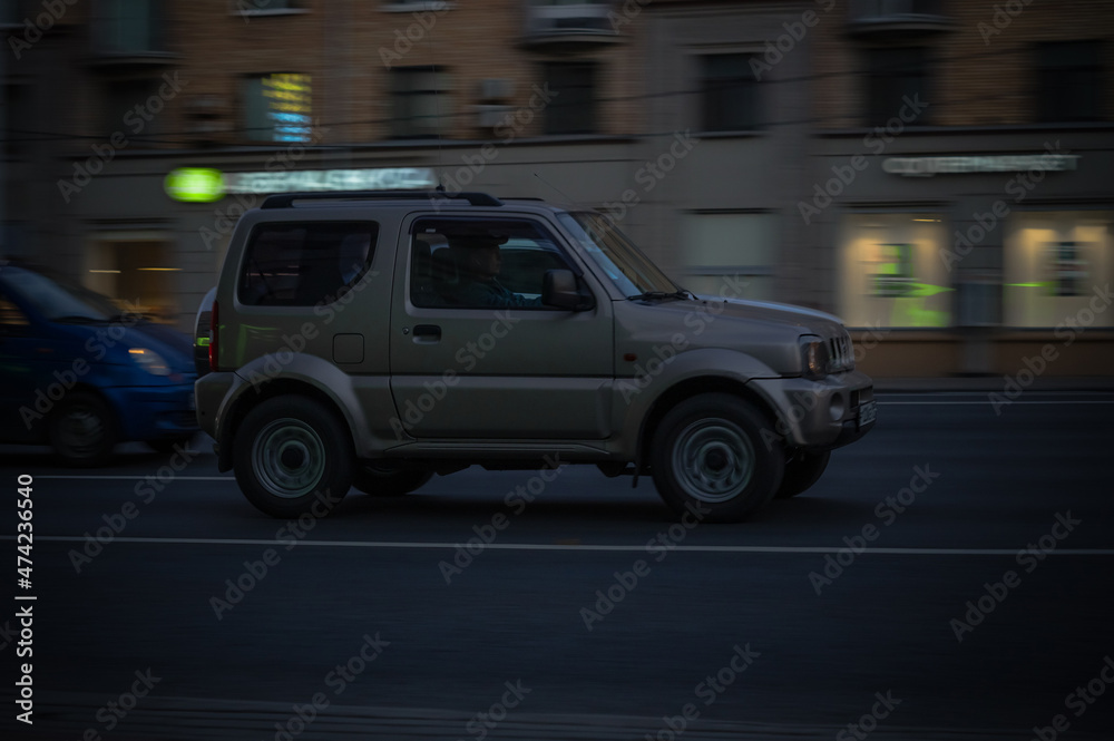 Side view of beige Suzuki Jimny JB23 SUV driving on the urban road ...