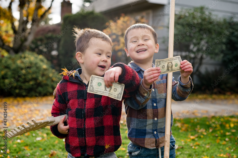 Two boys holding up money after doing yard work Stock Photo | Adobe Stock