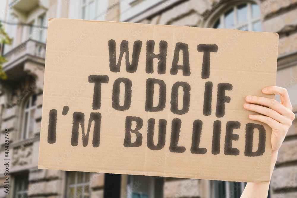 The phrase " What to do if I’m bullied " on a banner in men's hand with ...
