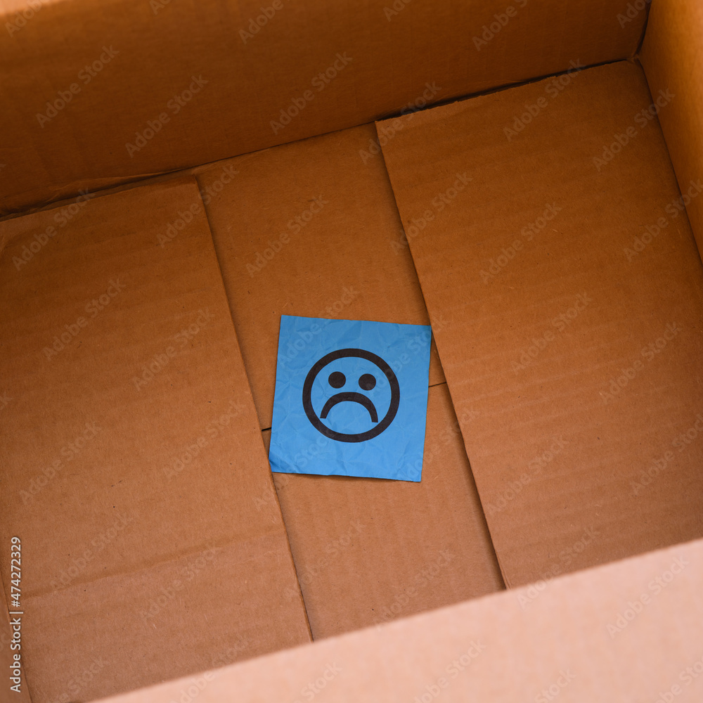 A blue paper note with a sad face on it in a cardboard box Stock Photo ...