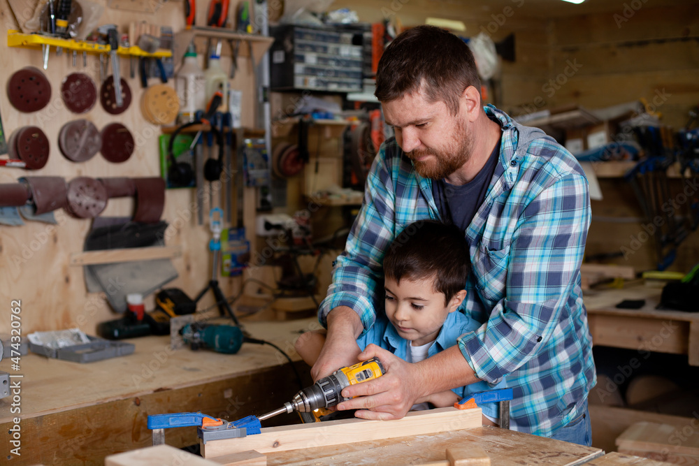 Father carpenter and son boy work in the workshop. Master dad teaches ...