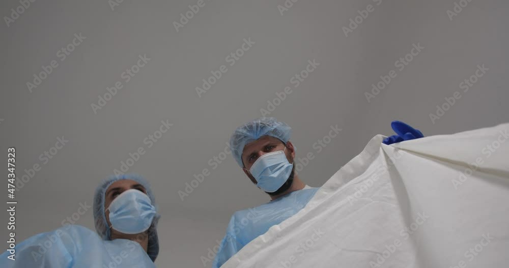 Low angle shot point of view, doctor and nurse bent over the dead body ...