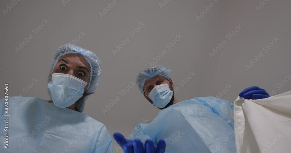 Low angle shot point of view, doctor and nurse bent over the dead body ...