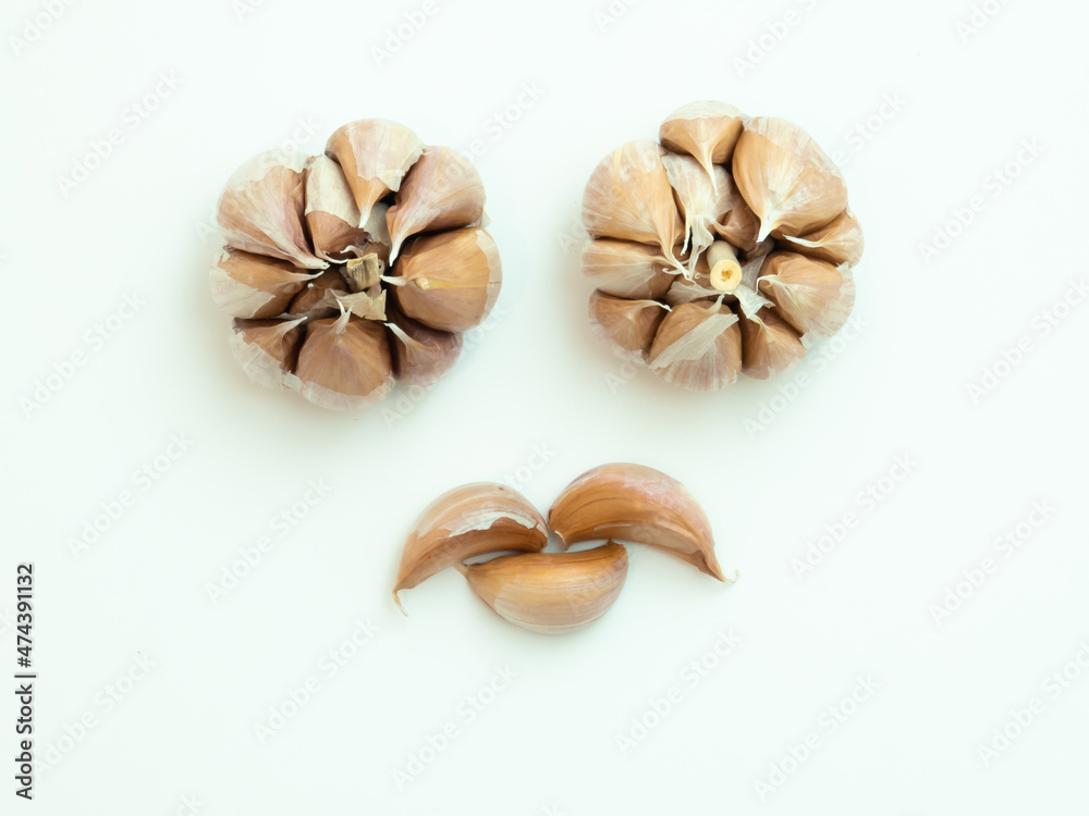 Funny smiley face emoticon made from raw garlic on white background ...