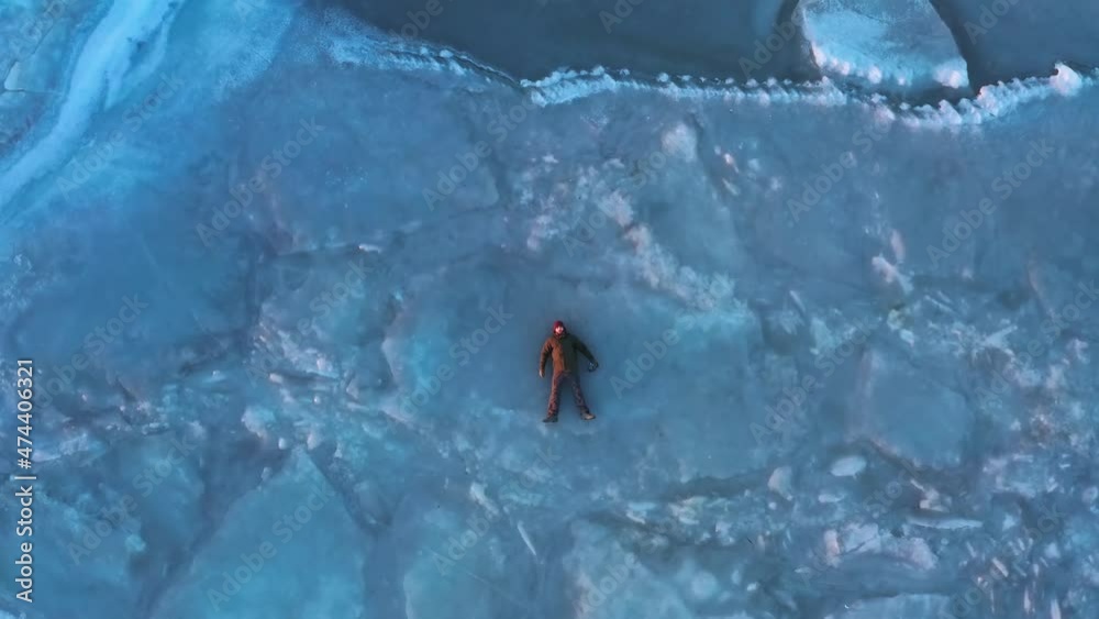 Aerial view of man lying on ice in frozen sea alone, A human lost on ...