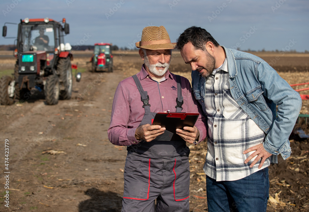 Farmers talking in field in front of tractors Stock Photo | Adobe Stock