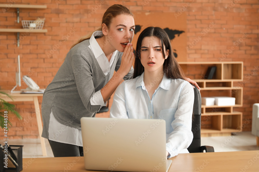 Female colleagues gossiping in office Stock-Foto | Adobe Stock