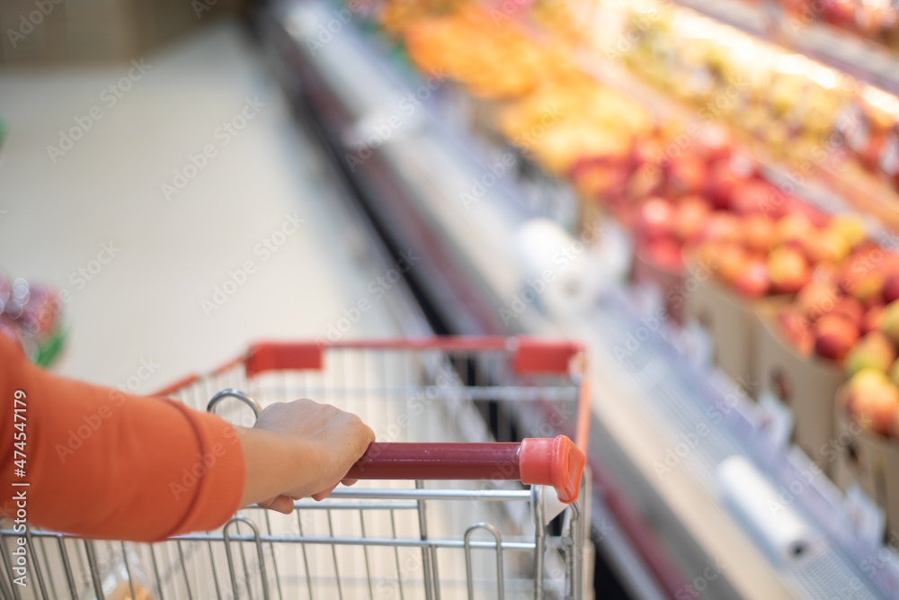 A woman with a trolley is shopping in a supermarket in the fruit and ...