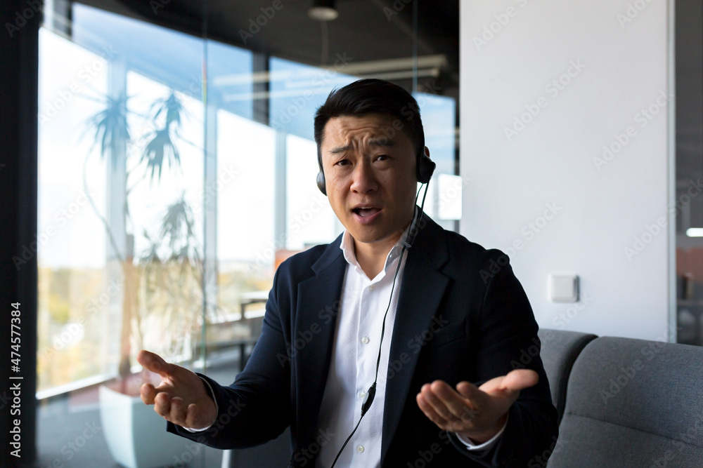 A man with a question looks at the camera, an Asian businessman is ...