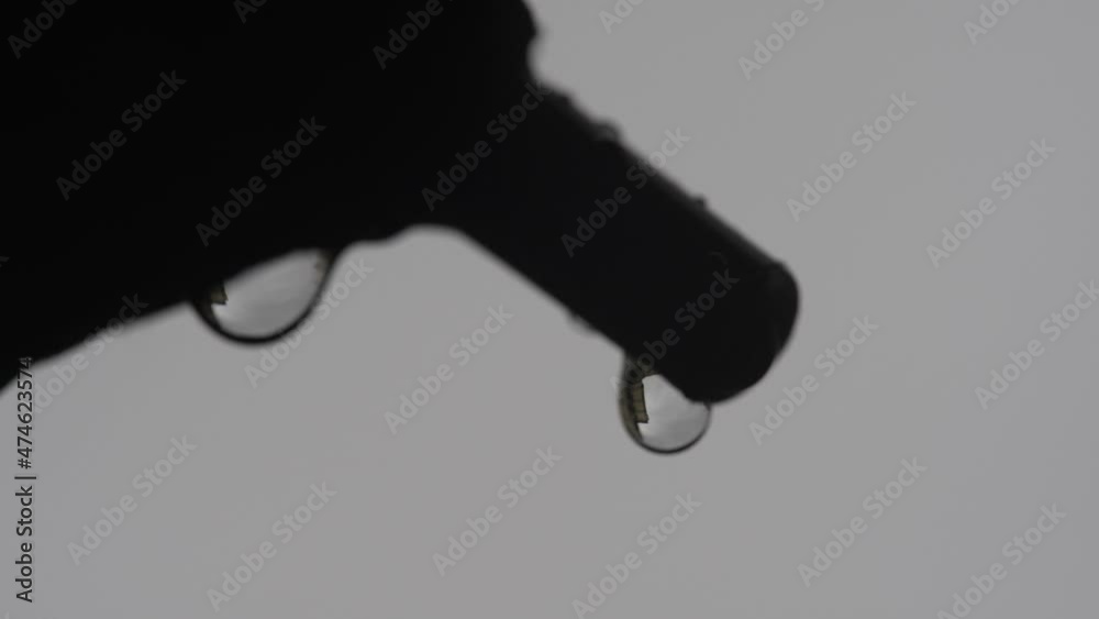 A precise macro look at two water drops hanging on a plastic tube, both ...