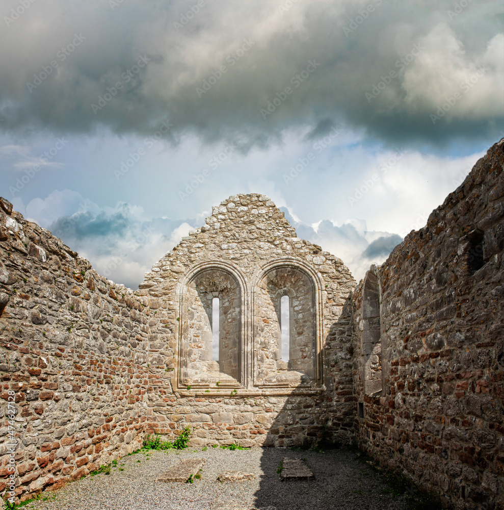 Two arched windows in the ruins of a stone chapel in an Irish cemetery ...