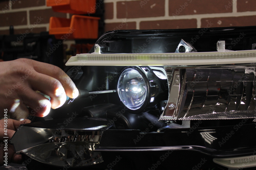 Car headlight in repair close-up. An auto mechanic wearing gloves ...