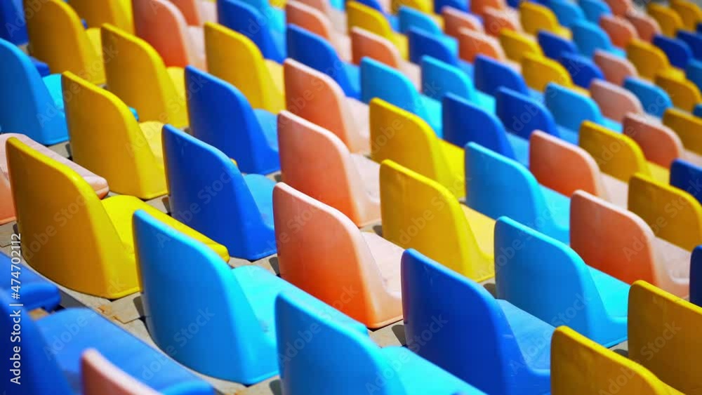 Multi-colored chairs in the stadium. Rows of empty plastic seats in the ...