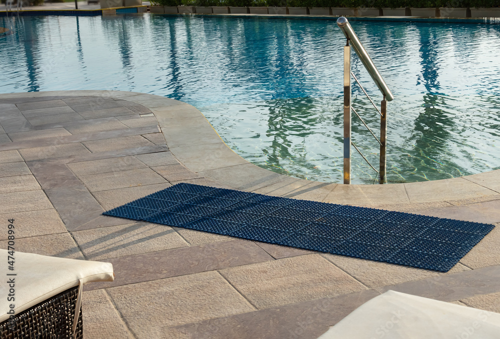 blue rubber non-slippery mat on the tiles in front of the pool entrance ...