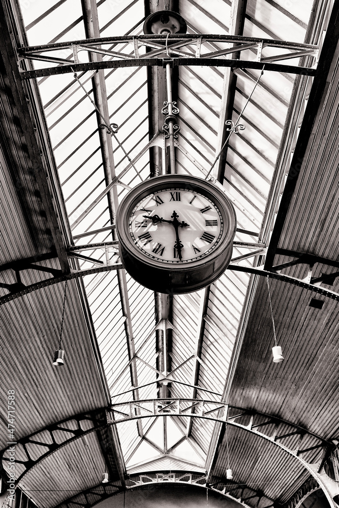 Black and white concept of a vintage public clock under a glass ceiling ...