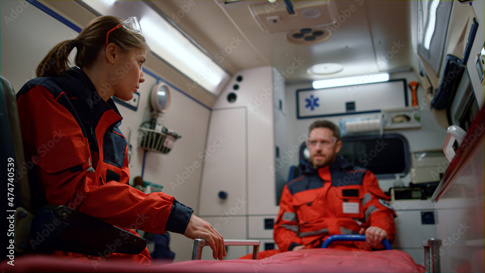 Emergency medical service driving in ambulance car. Doctors wearing ...