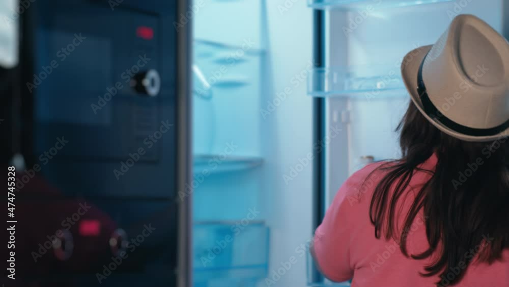 sad woman opens the refrigerator and takes a beer, opens and drinks ...