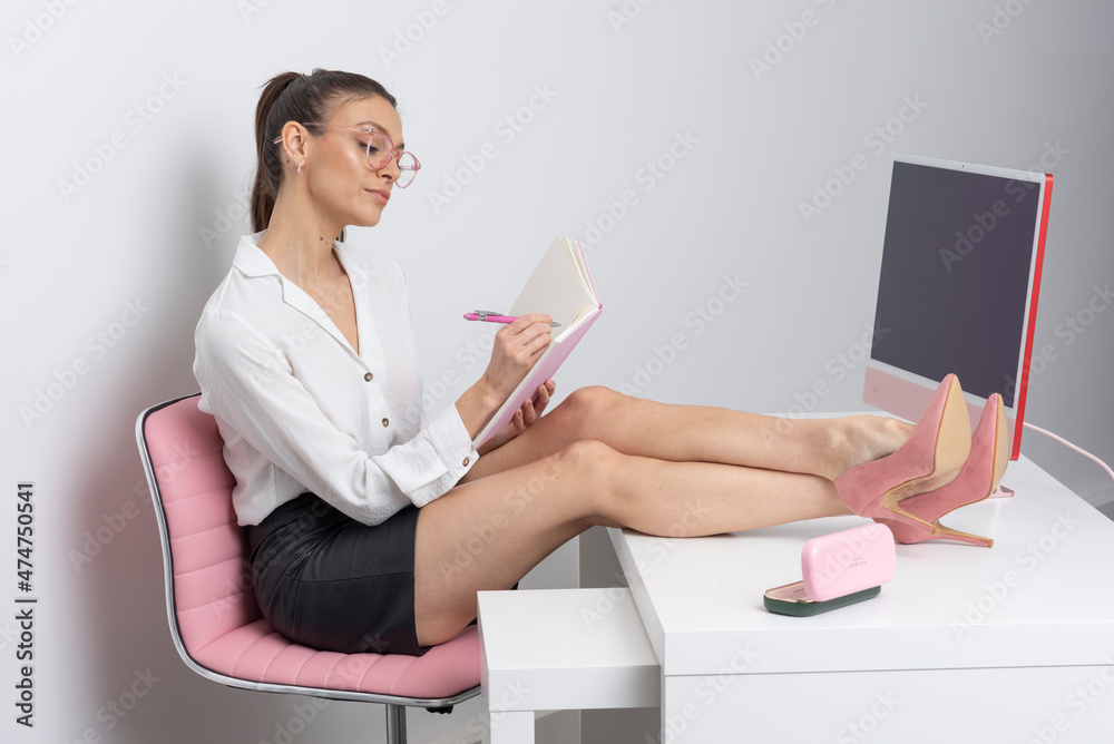England, UK. 2021. Female office worker with long legs crossed on her ...
