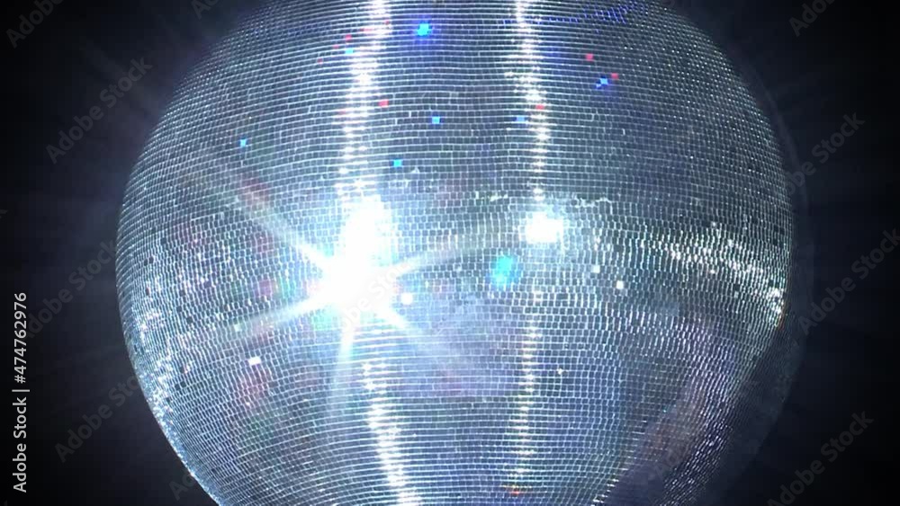 A large mirror ball (disco ball) rotates above a theatre stage with ...