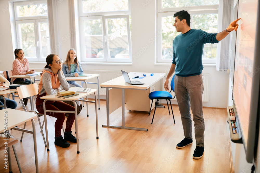 Happy teacher gives lecture on interactive whiteboard during class at ...