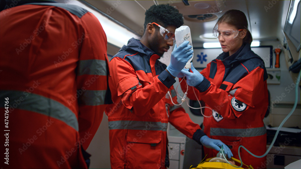 Professional paramedics performing first aid procedure in emergency car ...