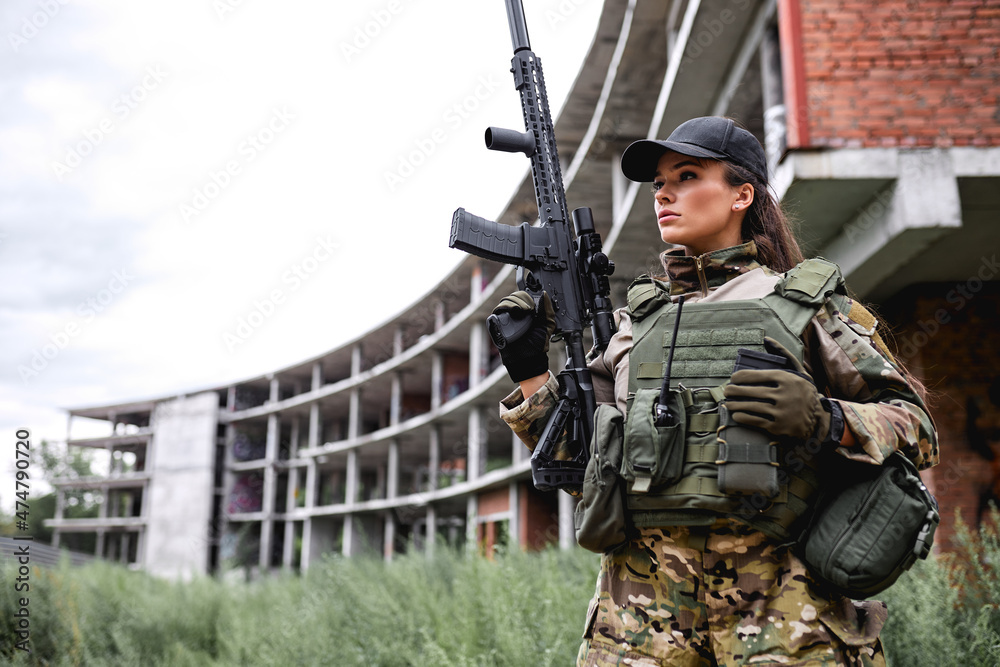 Military lady woman in tactical gear posing for photo in grass next to ...
