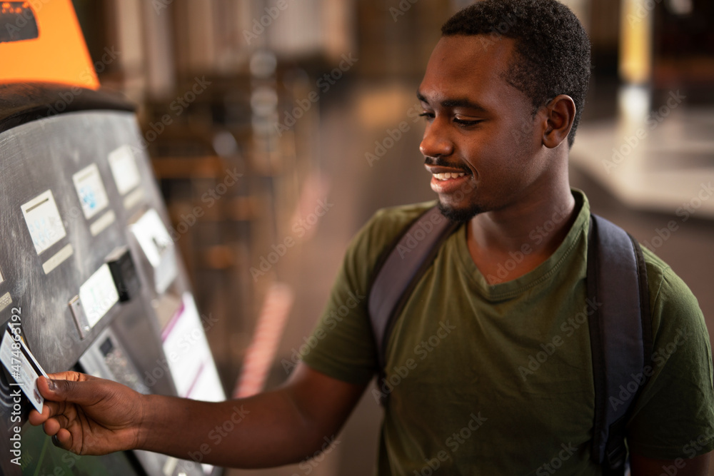 Smiling African man using ATM machine. Happy young man withdrawing ...