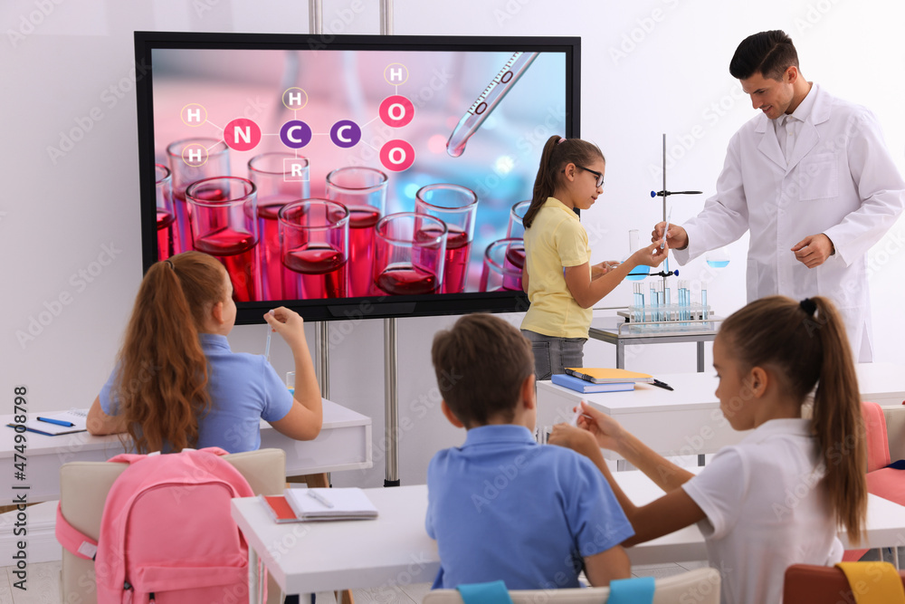 Teacher and pupils in classroom with interactive board during practical ...