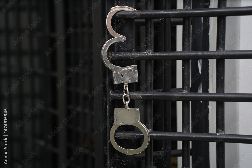 Handcuffs are hanging on the bars of the door of the detention center ...