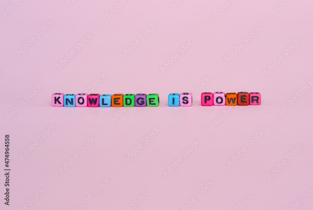 Words knowledge is power written with letter blocks in different colors on a light pink ...