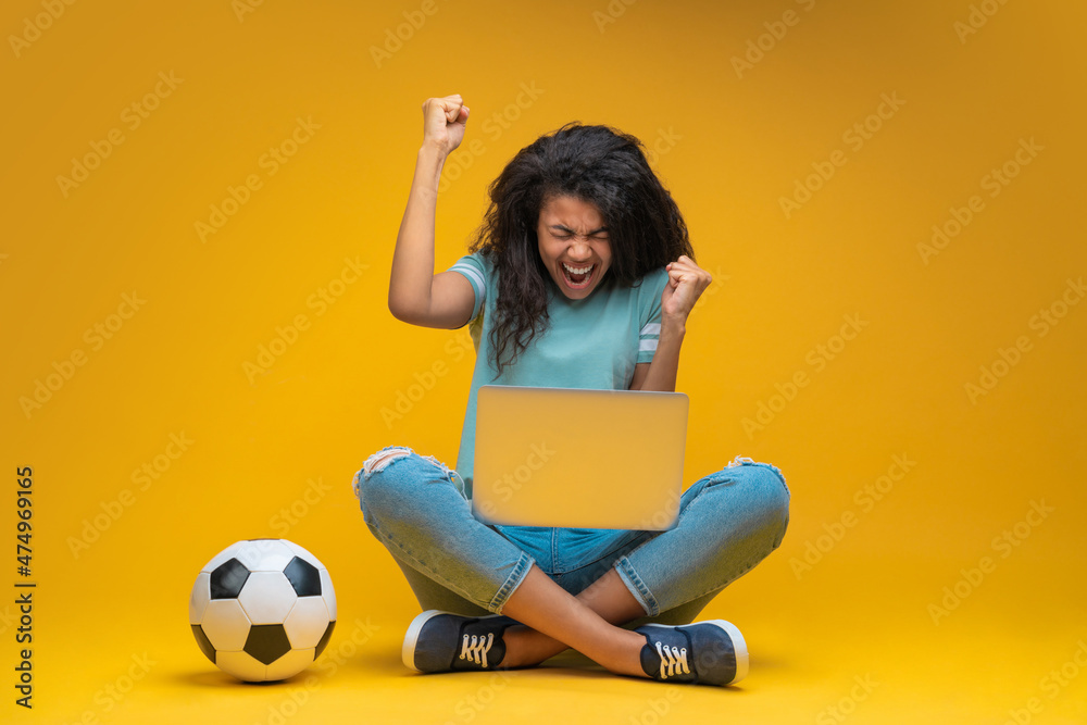 Happy soccer fan girl sitting on a floor, watching play live broadcast ...