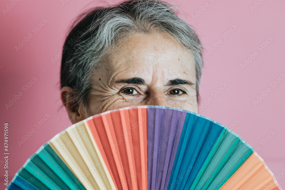Old senior white hair woman holding an lgbti hand fan colourful ...