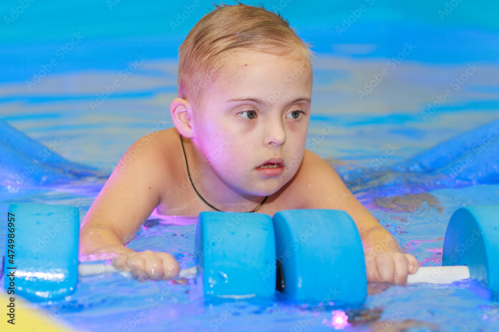 A boy with Down syndrome learns to swim in the pool, rehabilitation of ...