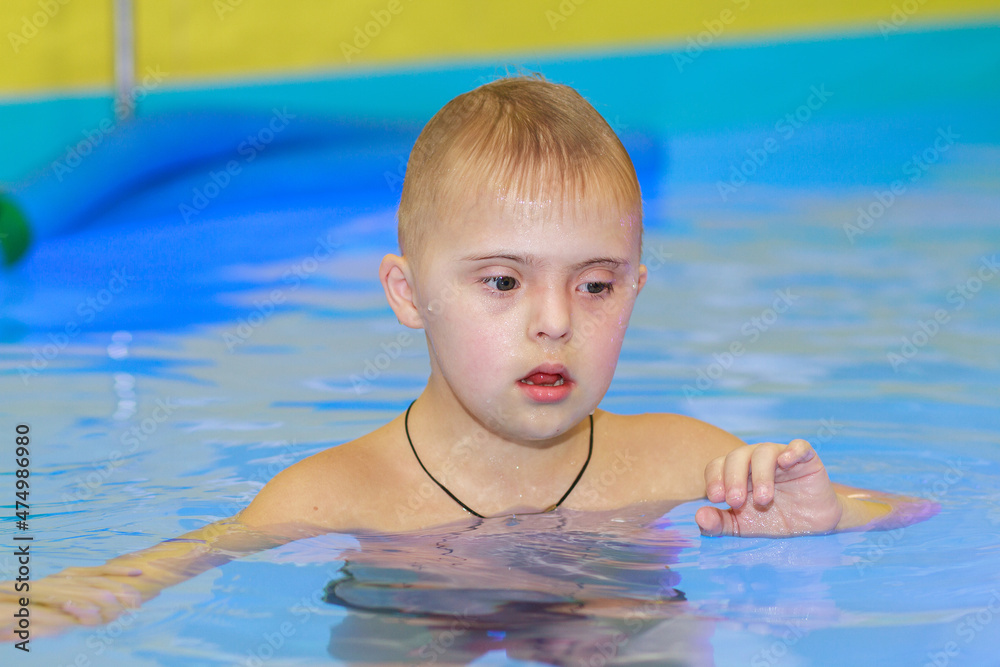 A boy with Down syndrome learns to swim in the pool, rehabilitation of ...