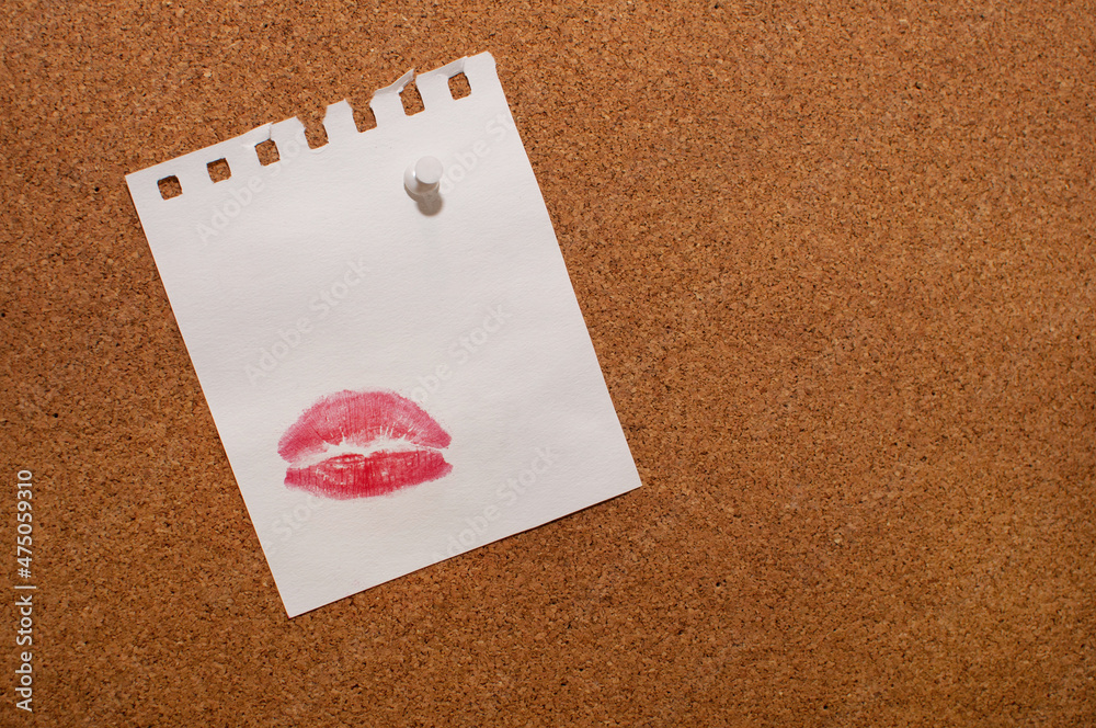 a lipstick mark on a piece of paper attached to a cork board with a ...