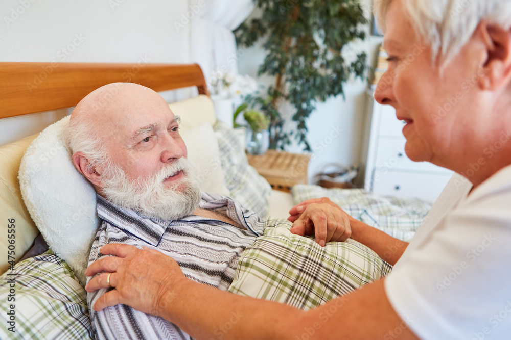 Geriatric nurse cares for and comforts sick senior in bed Stock Photo ...