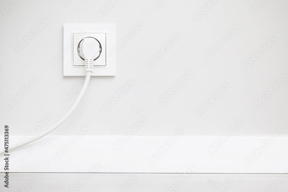 Electrical socket isolated on gray wall. White wire plug plugged in ...