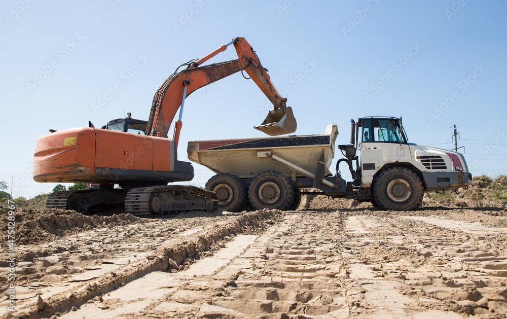 gray articulated dump truck and crawler excavator at a construction ...