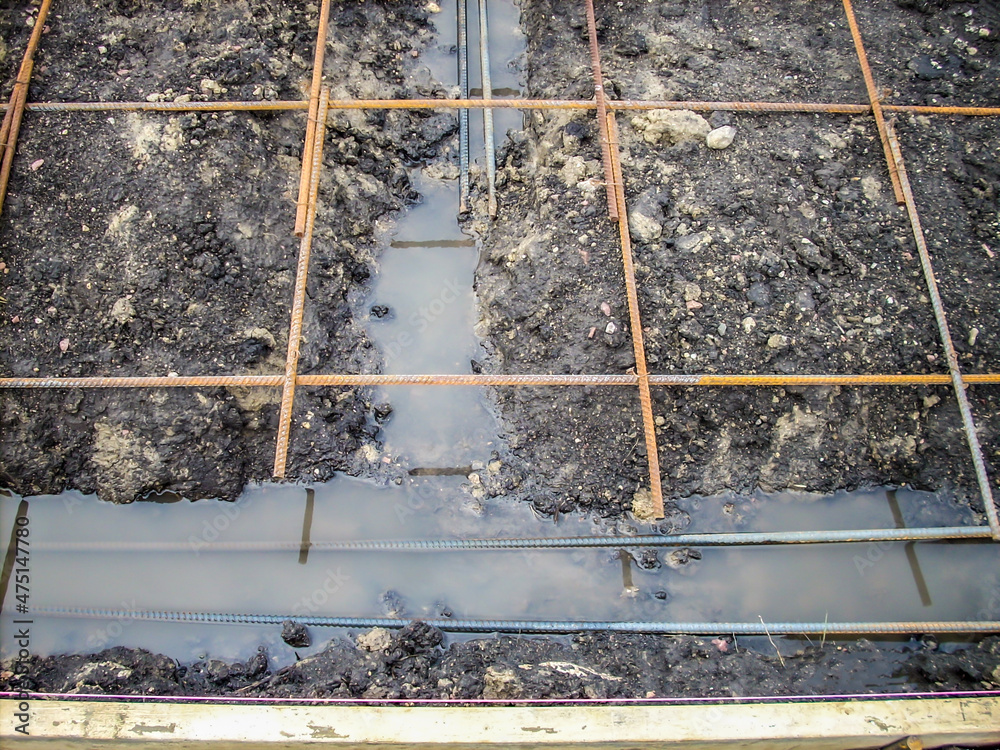 Construction site rebar suspended over a footing trench filled with ...