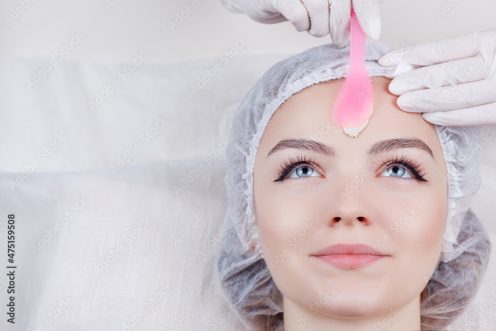 Beautician applies a white skin mask on client's face with help of ...