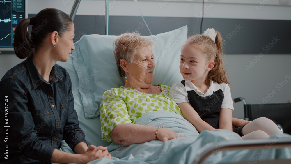 Niece and sick grandma hugging at family visit in hospital ward. Little ...