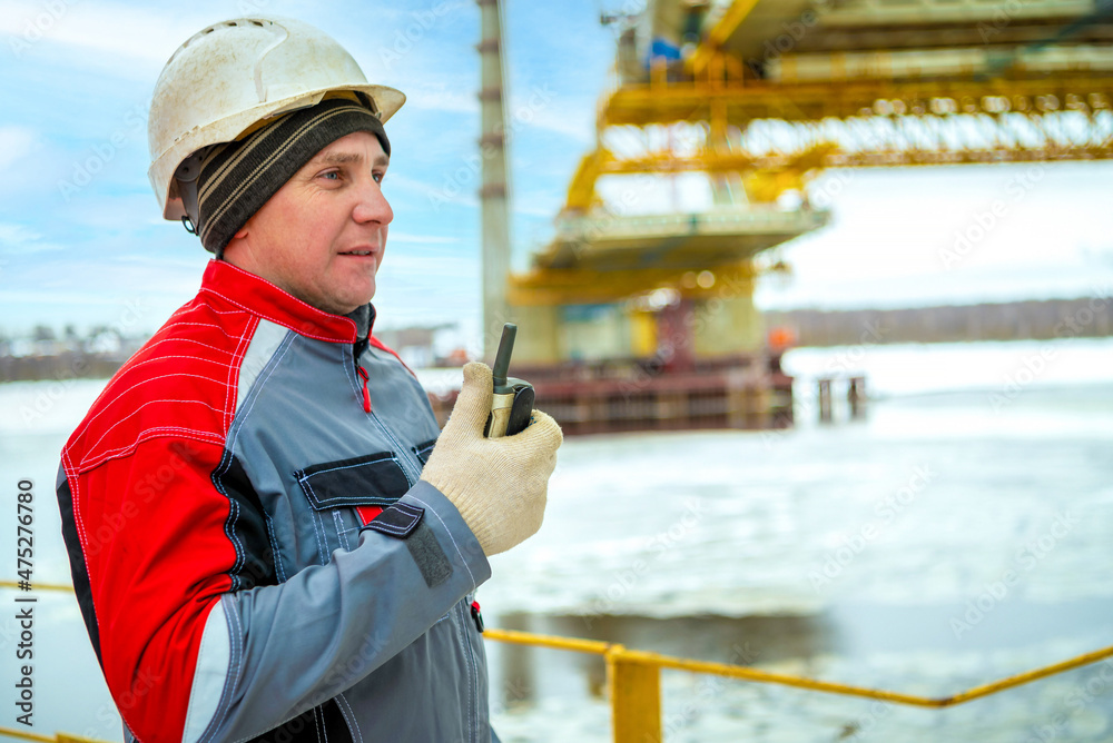 A worker engineer in overalls and a protective helmet at a construction ...