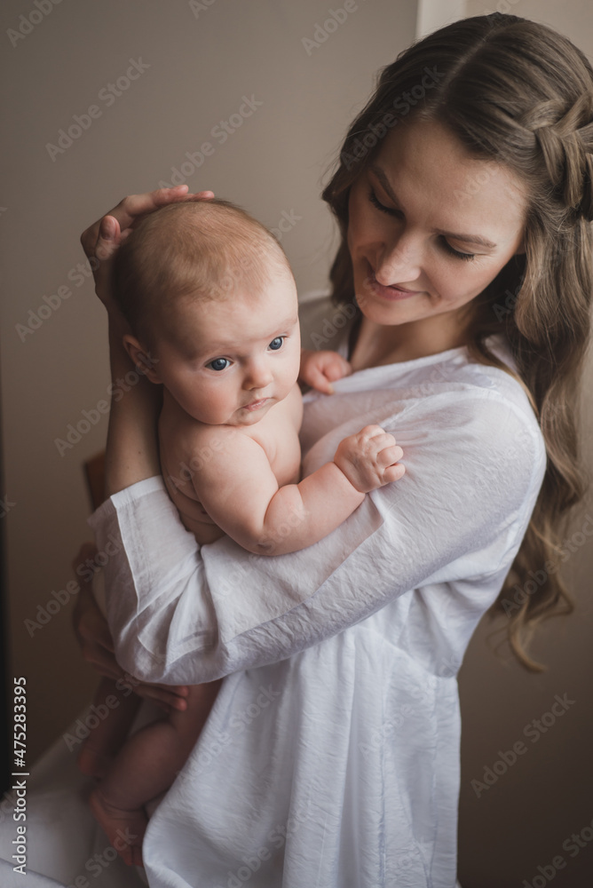 Foto de Beautiful young mother holds newborn baby girl in white lighter ...